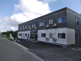 Um edifício moderno com telhado plano, vários aparelhos de ar condicionado e portão fechado.