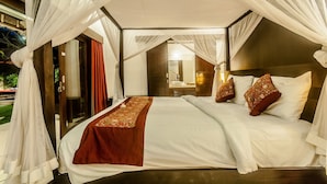 Quarto com cama de dossel, vista para o exterior e banheiro visível por uma porta aberta.