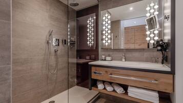 Uma casa de banho moderna com chuveiro envidraçado, lavatório com espelho e barra de toalhas.