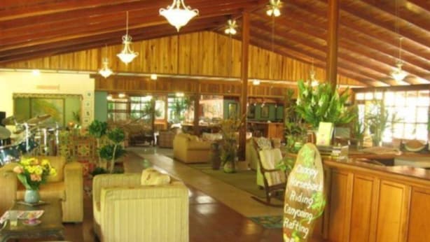 Um hall amplo com vigas de madeira, assentos confortáveis e um balcão de recepção.