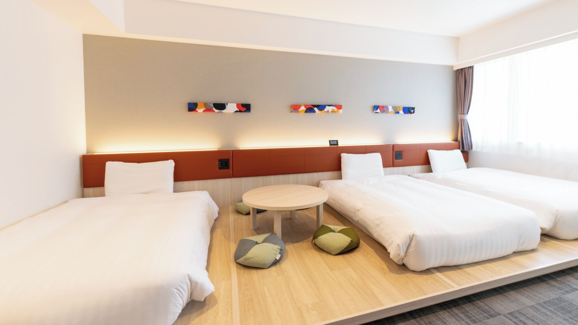 Quarto de hotel com duas camas, uma mesa redonda pequena e painel de controle fixado na parede.