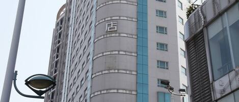 Um edifício de hotel alto com fachada curva e uma faixa azul destacada.