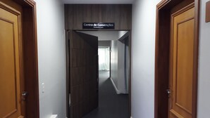 Um corredor com portas de madeira em ambos os lados, dando acesso a uma sala identificada como 'Centro de Convenções'.