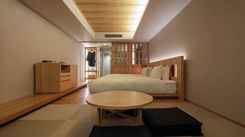 Quarto moderno e compacto com cama de madeira, uma mesinha redonda e um guarda-roupa.