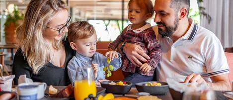Uma família jantando em um restaurante com diversos pratos e bebidas sobre a mesa.