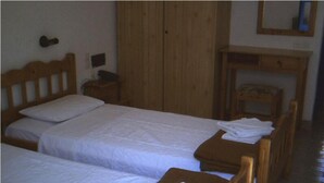 Um quarto com duas camas de madeira, uma mesa de cabeceira de madeira, uma cadeira de madeira e uma mesa.