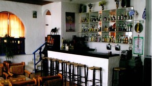 Uma área de bar com cadeiras de madeira, um balcão e prateleiras cheias de garrafas.