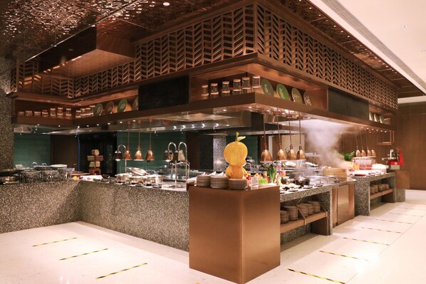 Cozinha moderna com bancadas de granito, eletrodomésticos de aço inoxidável e uma ilha central com uma escultura amarela decorativa.