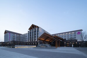 Um hotel moderno com entrada imponente, vários andares e fachada bem iluminada.