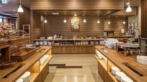 Espaço de café da manhã moderno com balcões de madeira, sistema de buffet e luminárias pendentes.