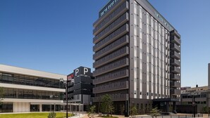 Hotel de vários andares com design moderno, com varandas em cada piso e uma sinalização chamativa.