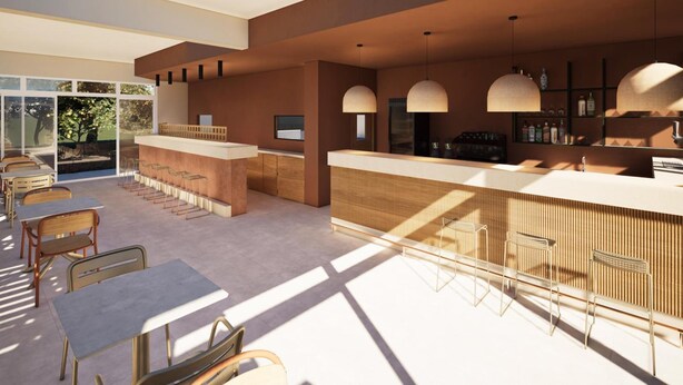 Uma área de bar moderna com balcão longo, banquetas e luminárias pendentes.