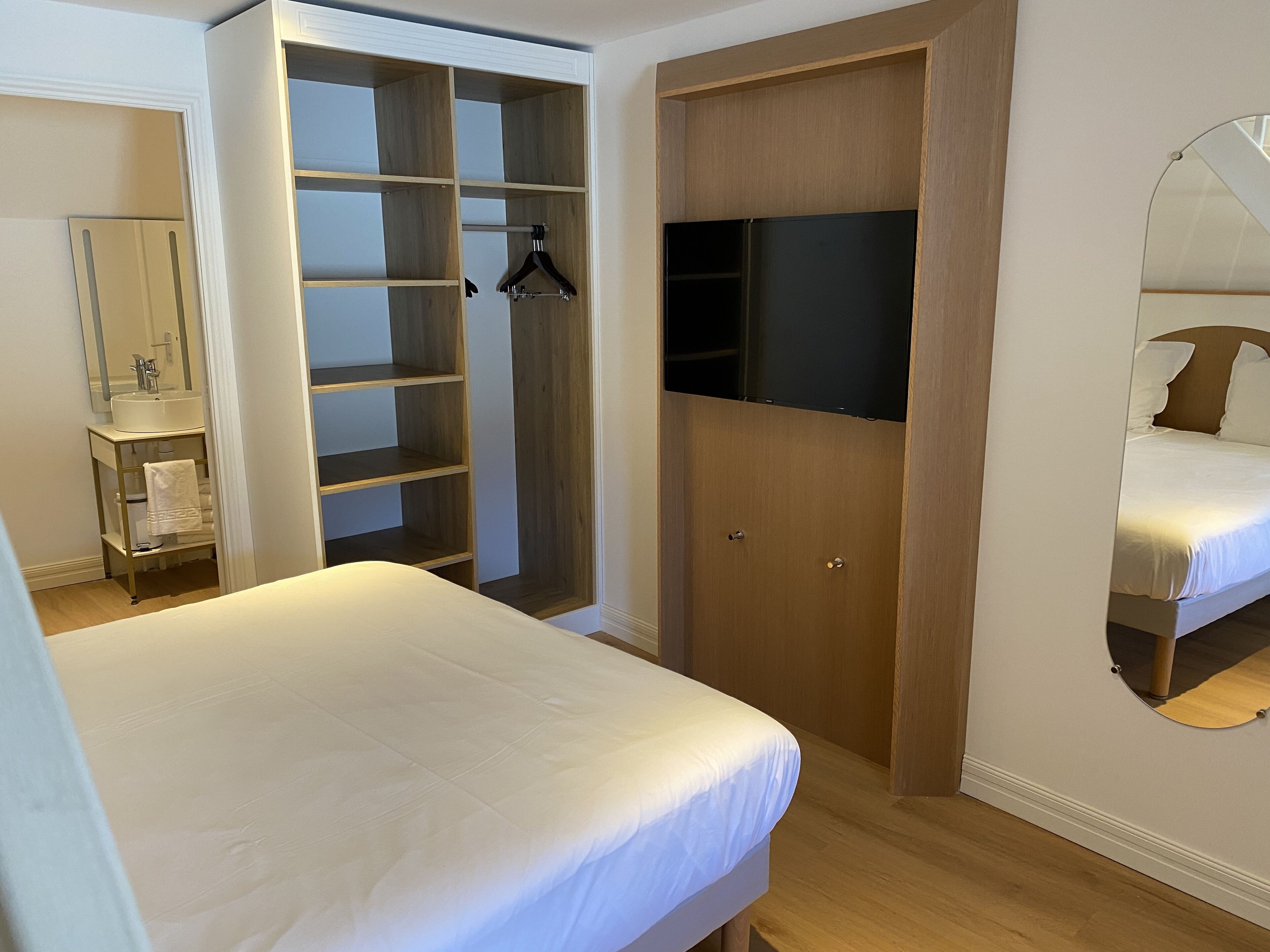 Quarto com cama, guarda-roupa, espelho e televisão.
