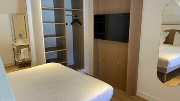 Quarto com cama, guarda-roupa, espelho e televisão.