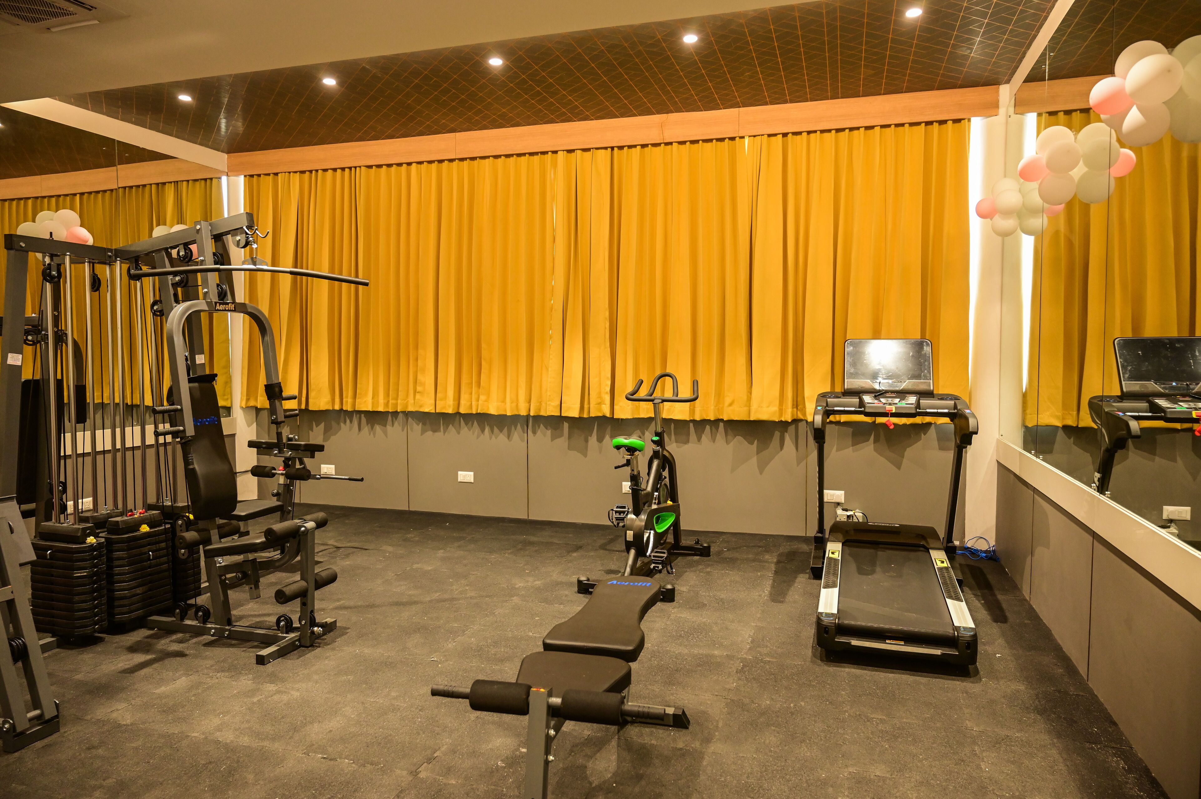 Uma academia com equipamentos de ginástica, esteira e bicicleta ergométrica.