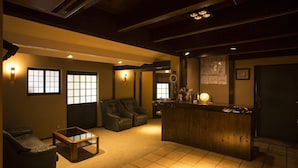 Um quarto com um sofá, uma mesa de centro, um balcão de recepção de madeira e um relógio de parede.