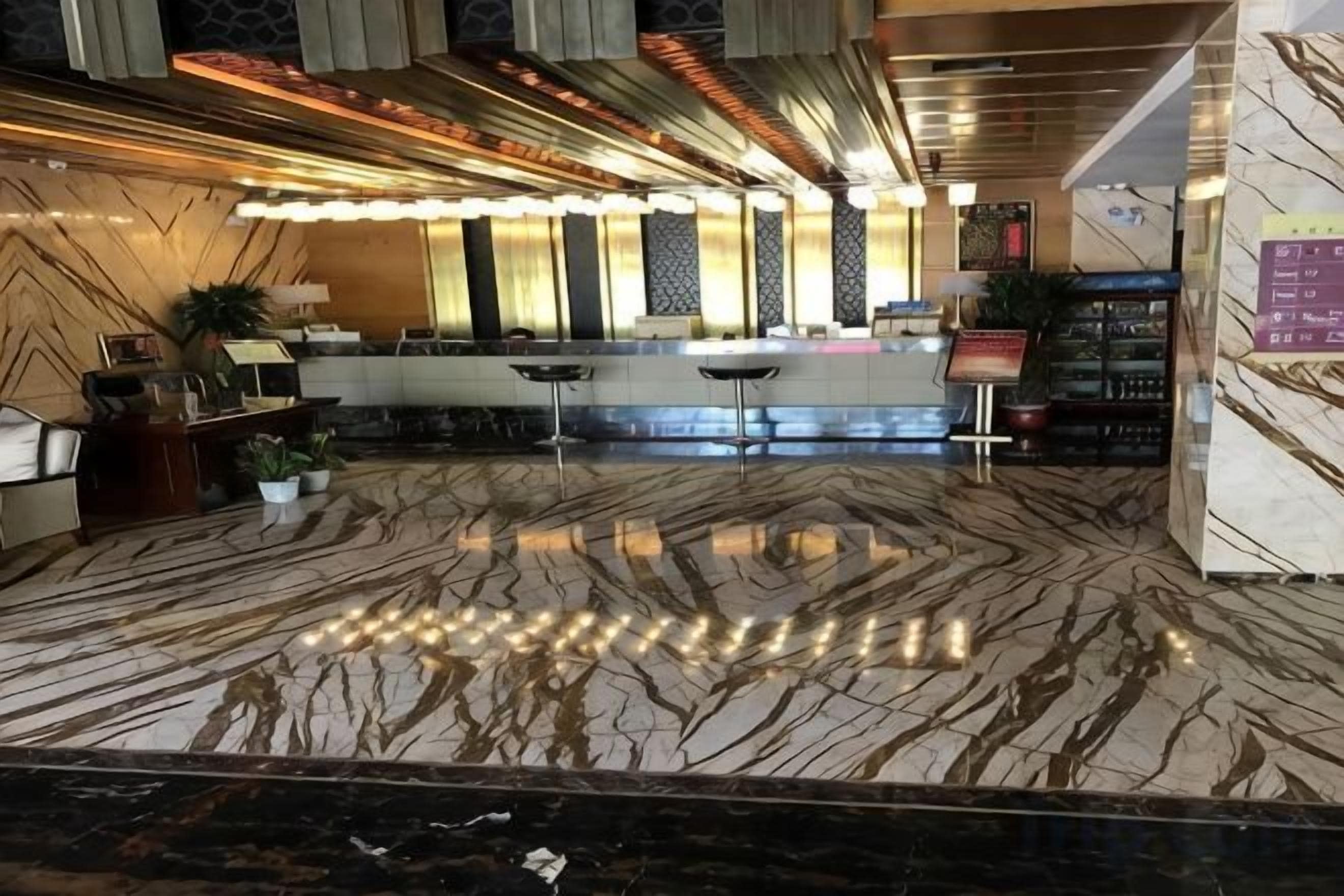 Um hall de hotel com piso de mármore, balcão de recepção e área de estar.