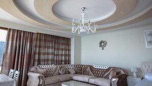 Sala de estar com um amplo sofá modular, um candelabro e um detalhe decorativo na parede.