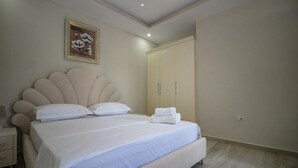Quarto com cama grande, mesa de cabeceira, guarda-roupa e um quadro na parede.