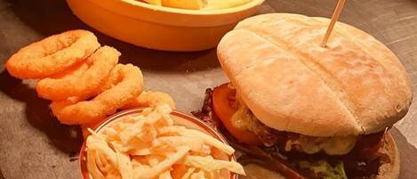 Uma refeição com hambúrguer, batatas fritas, anéis de cebola e salada de repolho.