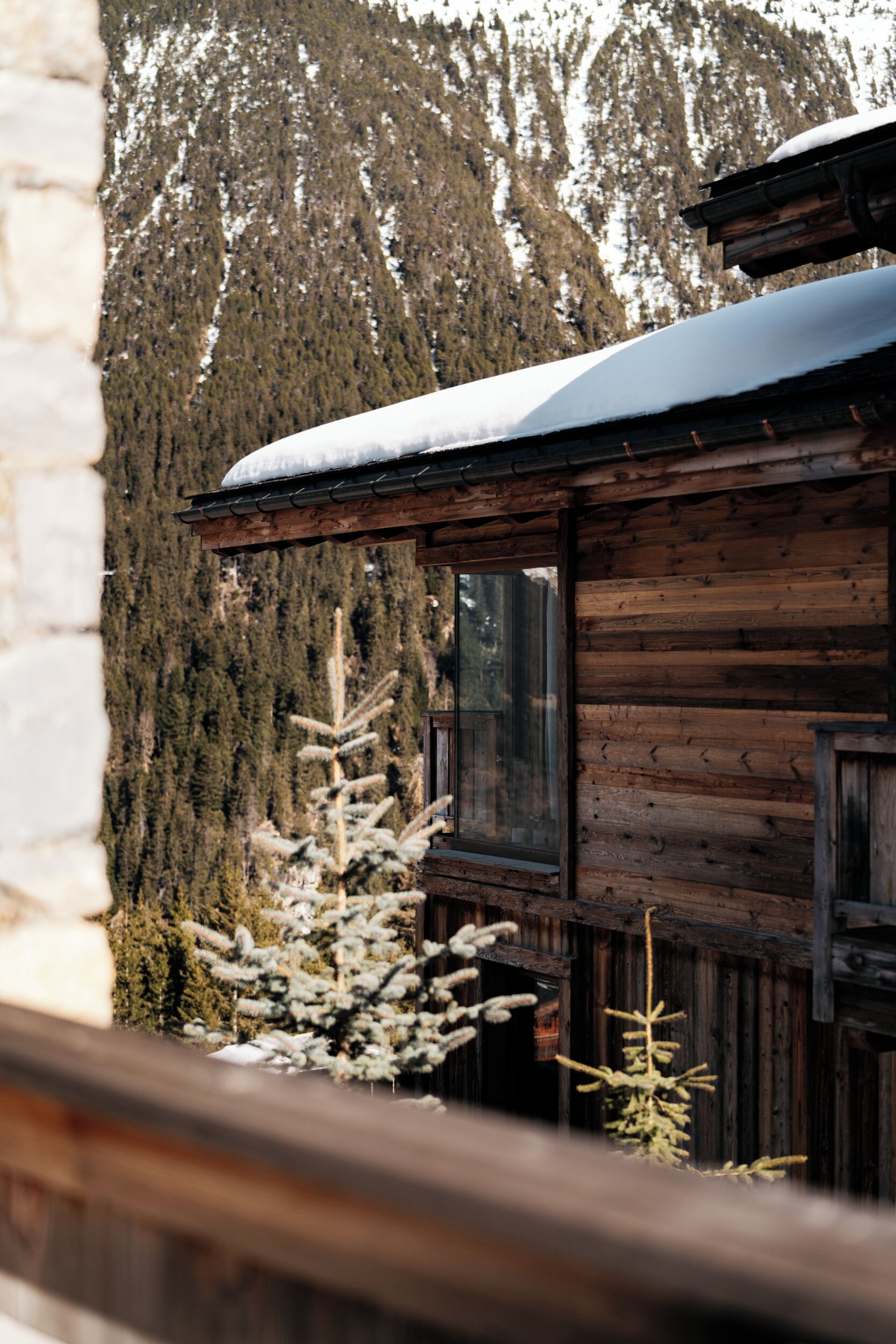 Uma cabana de madeira com telhado coberto de neve e uma janela.