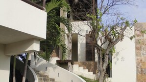 Uma escadaria de pedra sinuosa que leva a um edifício com telhado de palha e uma palmeira.
