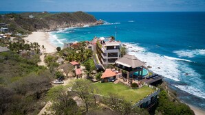 Um resort costeiro com vários edifícios, uma praia e vista para o oceano.