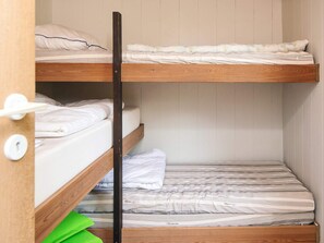 Quarto com beliches de madeira e roupa de cama branca.