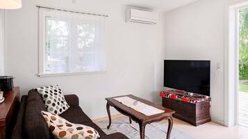 Uma sala de estar com sofá, mesa de centro, televisão de tela plana e armário de madeira.