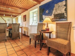 Um quarto acolhedor com móveis de vime, piso de azulejos e um quadro na parede.