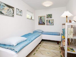 Quarto com cama, estante e obras de arte nas paredes.