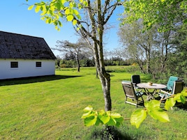 Uma casa branca com telhado preto, gramado verde e uma mesa com cadeiras.