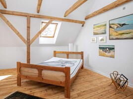 Quarto com cama de madeira, claraboia e obras de arte nas paredes.