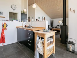 Cozinha moderna com ilha de madeira, armários pretos e luminária pendente.