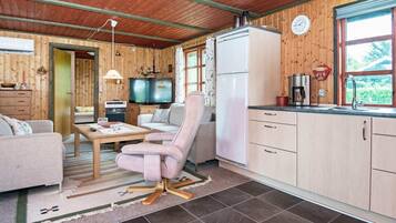 Interior acolhedor de uma cabana, com sala de estar, cozinha e sala de jantar.
