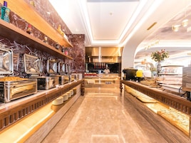 Uma área de buffet com bancadas de mármore, eletrodomésticos de aço inoxidável e um chefe preparando alimentos.