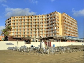 Um hotel grande com vários andares, varandas e localização à beira-mar.