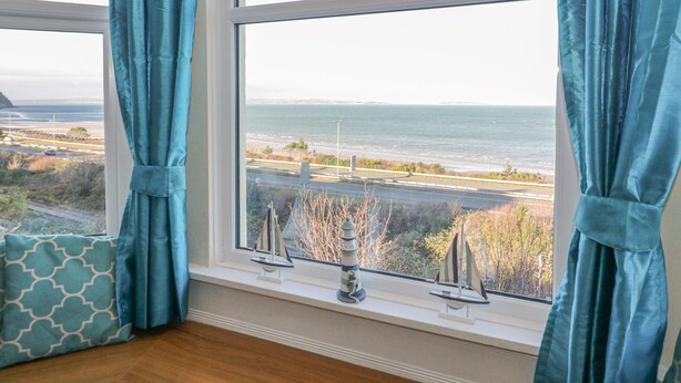Quarto com uma grande janela com vista para uma estrada costeira e oceano.