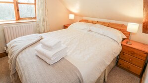 Quarto com cama, duas mesas de cabeceira, radiador e janela.