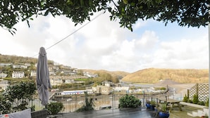 Um terraço com área de estar externa, vista para uma cidade e um rio ao fundo.