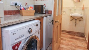 Cozinha compacta com máquina de lavar, micro-ondas e um pequeno armário com lanches.