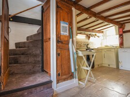 Uma escada leva a uma cozinha com vigas de madeira, um quadro branco e um código QR na porta.