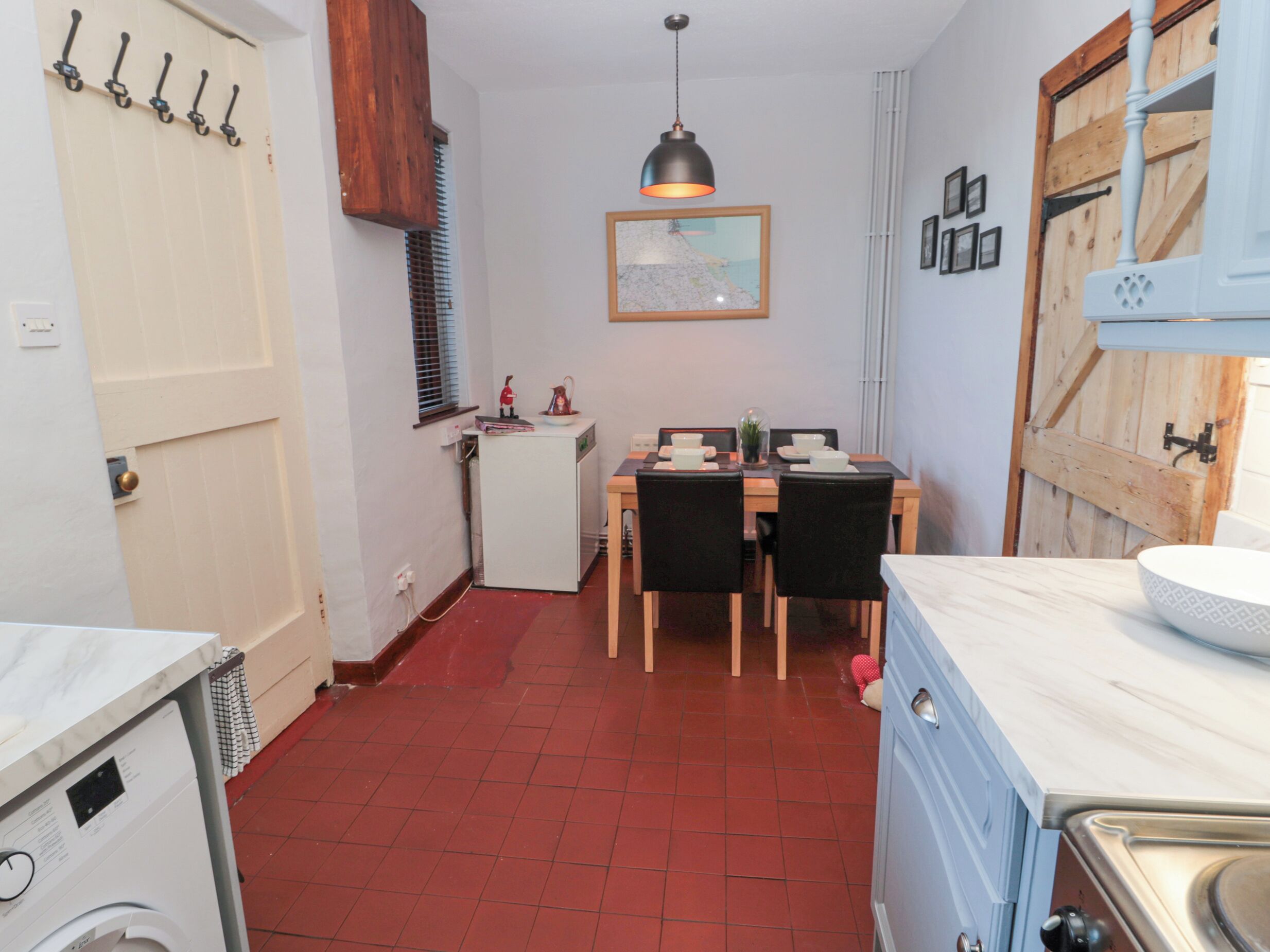 Uma cozinha compacta com área de jantar, máquina de lavar e fogão.