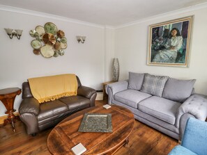 Sala de estar com dois sofás, uma mesa de centro, arte decorativa na parede e um quadro.