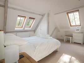 Quarto com cama, escrivaninha e duas janelas.