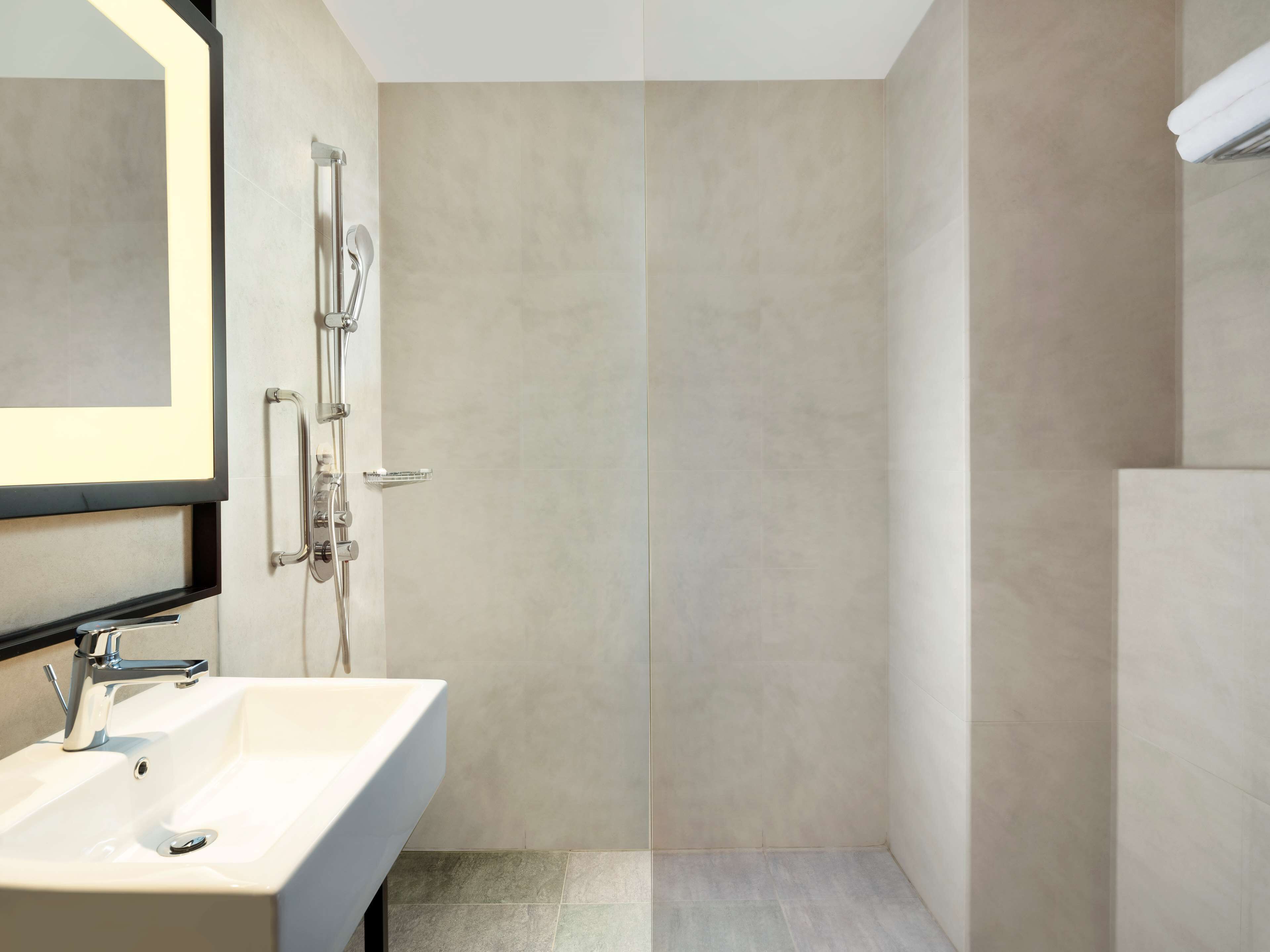 Casa de banho moderna com lavatório branco, espelho e zona de duche.