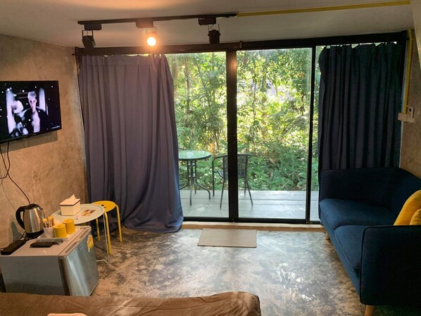 Uma sala de estar com televisão, uma mesinha com chaleira e um sofá.