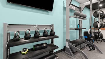 Uma academia com halteres, esteira e bolas de exercício.
