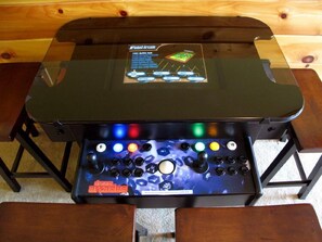 Um console de jogos com parte superior transparente e um painel de controle com vários botões e um joystick.