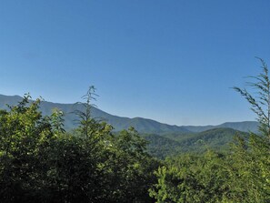 Paisagem montanhosa com vegetação densa e céus azuis cristalinos.